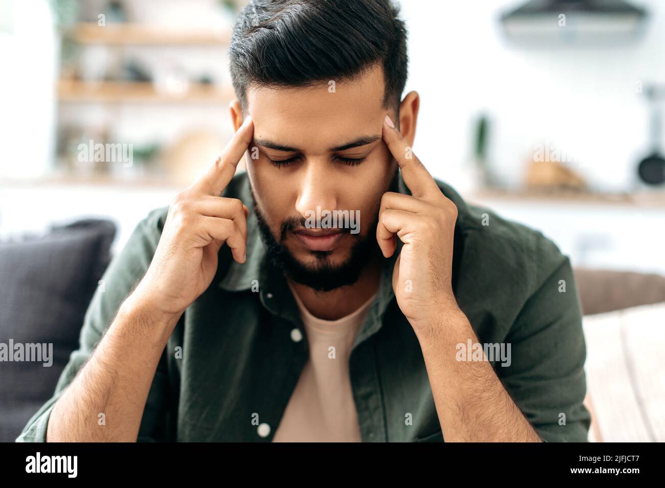 Headache, spasm. Sad exhausted arabian or indian nationality young man ...