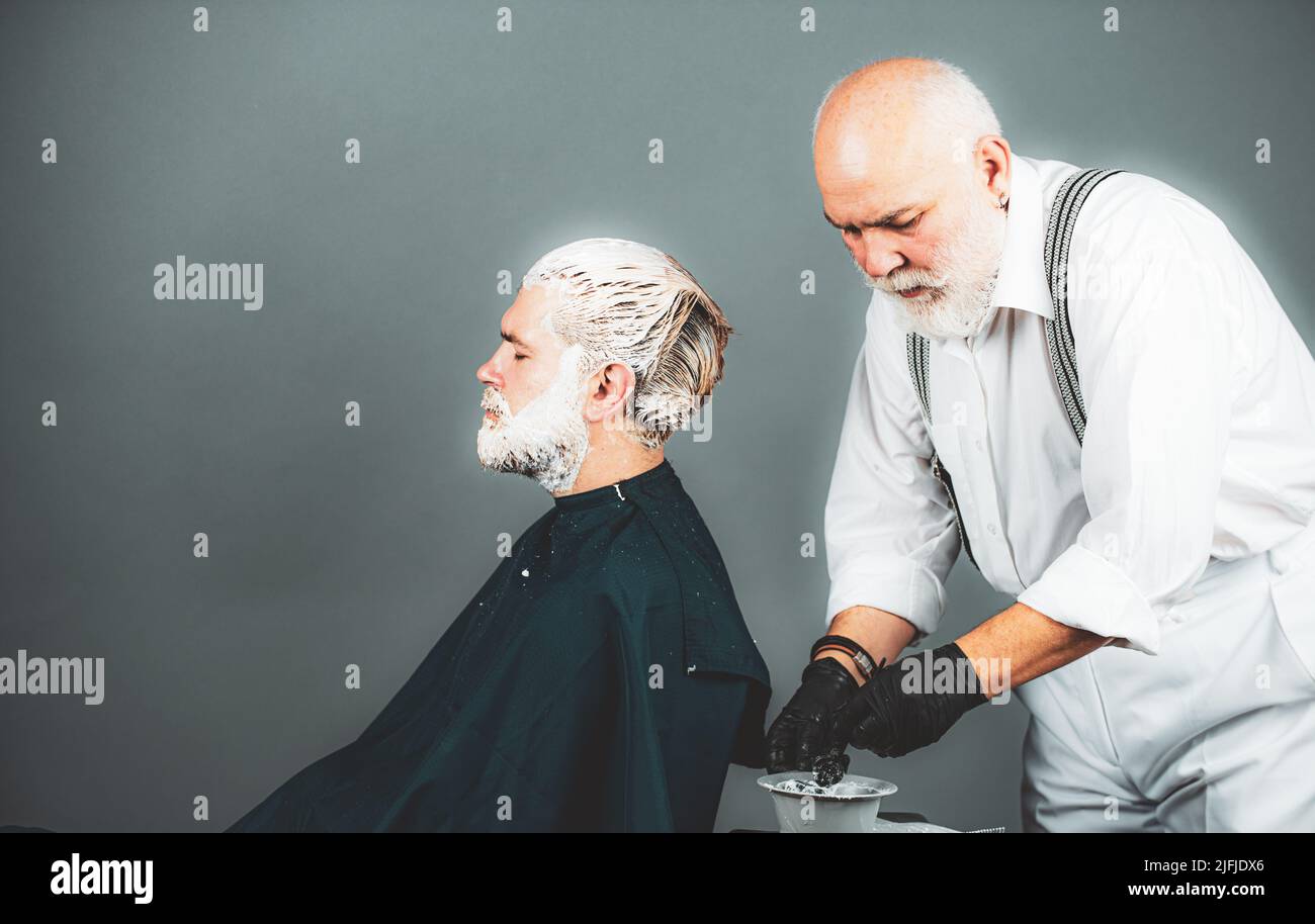 Senior hairdresser applying dye to man hair. Process of a guy having ...