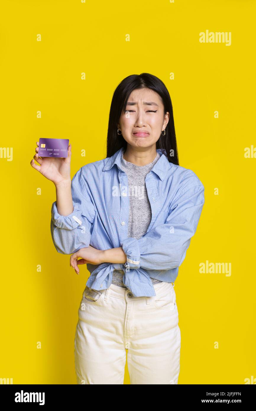 Crying asian girl holding purple credit, debit card with sad, unhappy ...