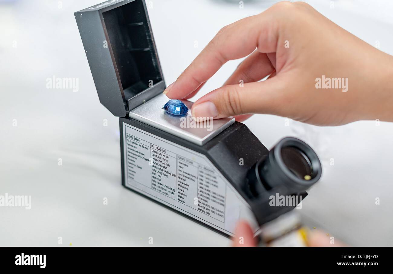 Female hand holding the blue precious stone and put on the ...