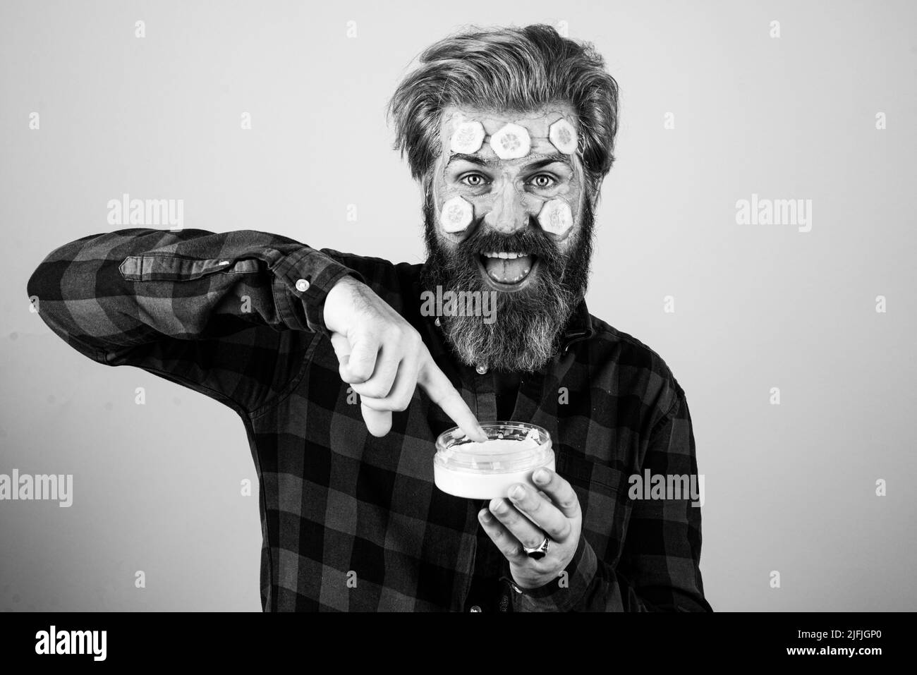 Funny man in a face mask in a beauty salon. Beautician applying scrub ...