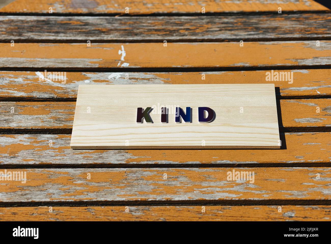 The word "Kind" written in rainbow colored lettering on an old rustic ...
