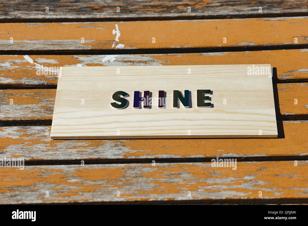 The word Shine in rainbow colored lettering on an old rustic orange ...