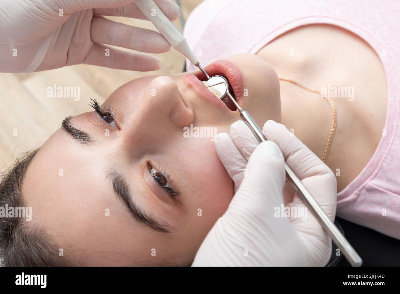 Dental check up in dential clinic. Dentist examining patient teeth with dental mirror during ...