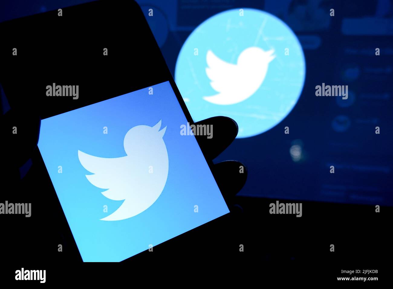 In this photo illustration, a Twitter logo seen on a smartphone and in ...