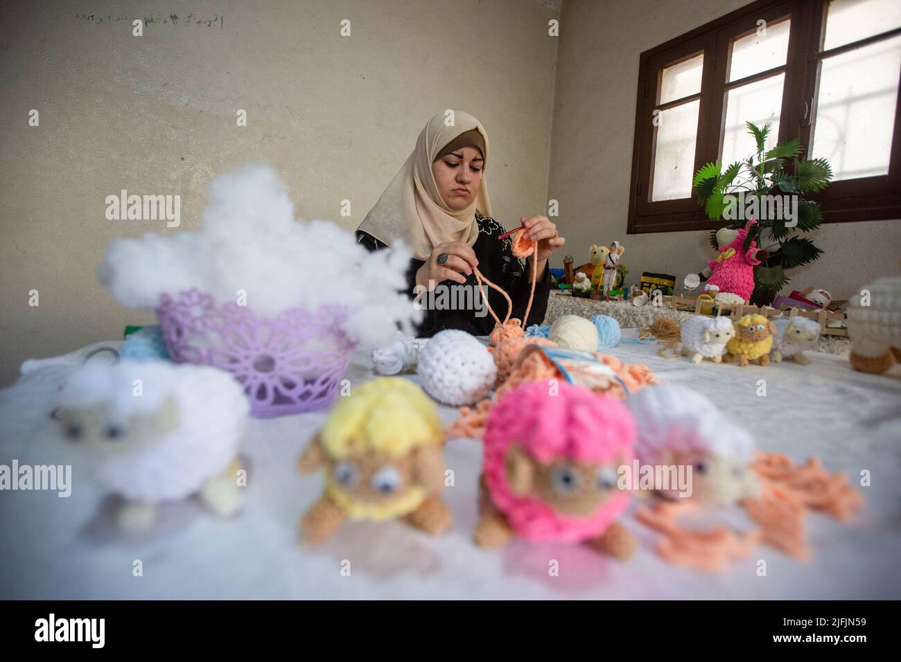 A Palestinian woman knits a doll in a shape of a sheep at her home in ...