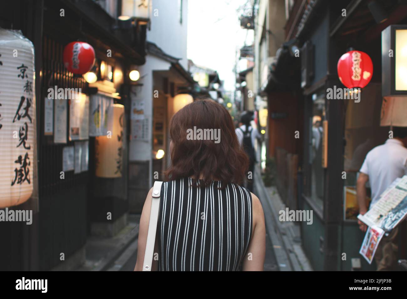 The back of a japanese woman walking down a narrow alleyway in Kyoto ...
