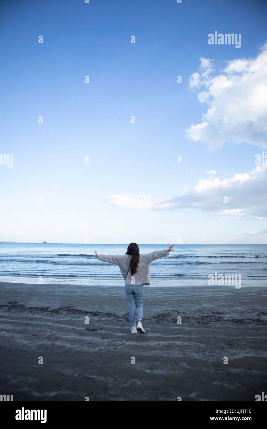 Young woman from behind is running at the beach to the sea in Larnaca ...