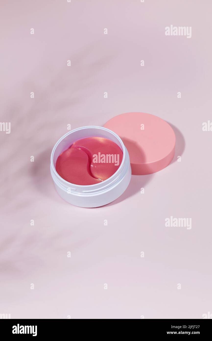 A container with pink eye patches with retinol and collagen on a pink ...