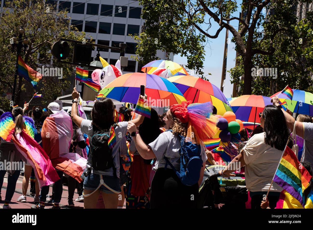 People participating in pride parade in the city, carrying rainbow ...
