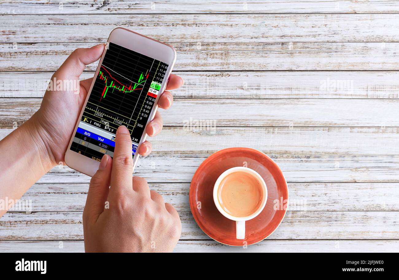 Women hand holds the phone for trading forex or stocks and see graph ...