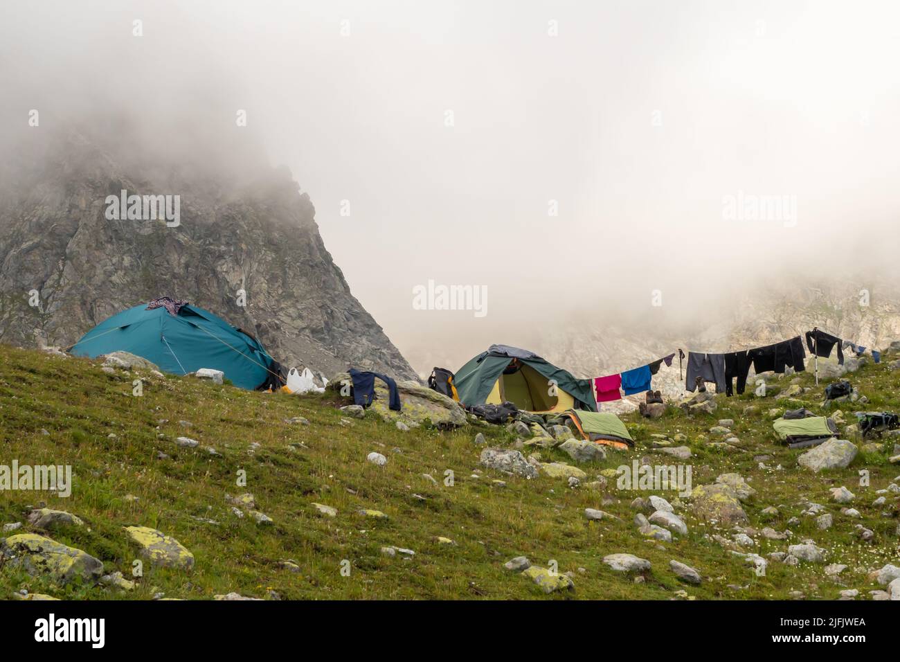 Clothes on the clothesline after the rain in the mountains. Tents in ...