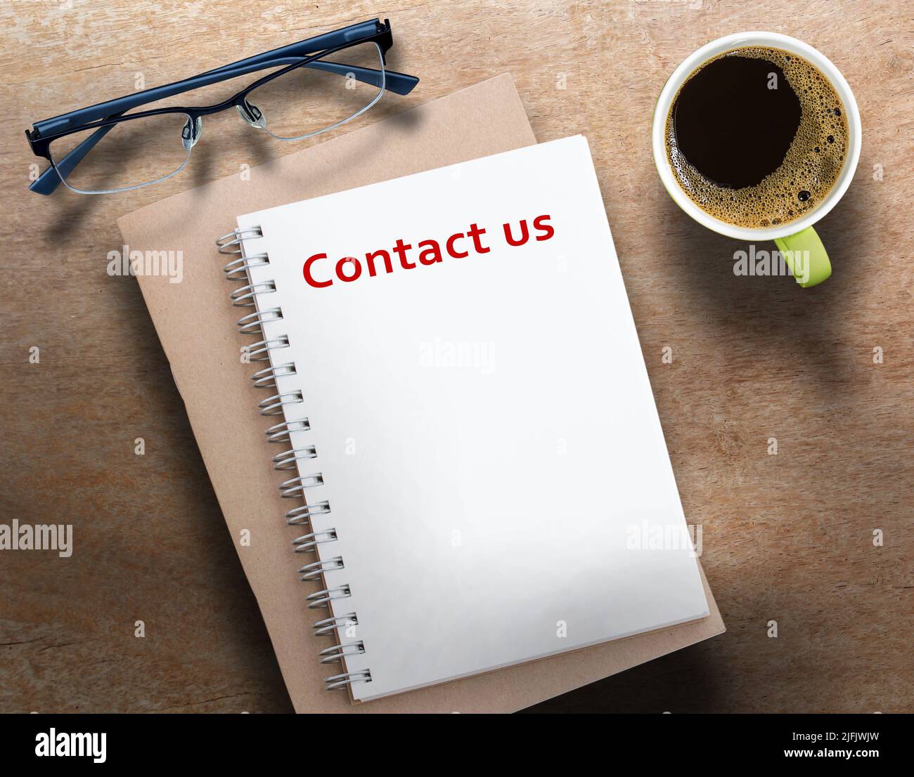 Top view Contact us text on notebook with coffee and glasses on wood ...