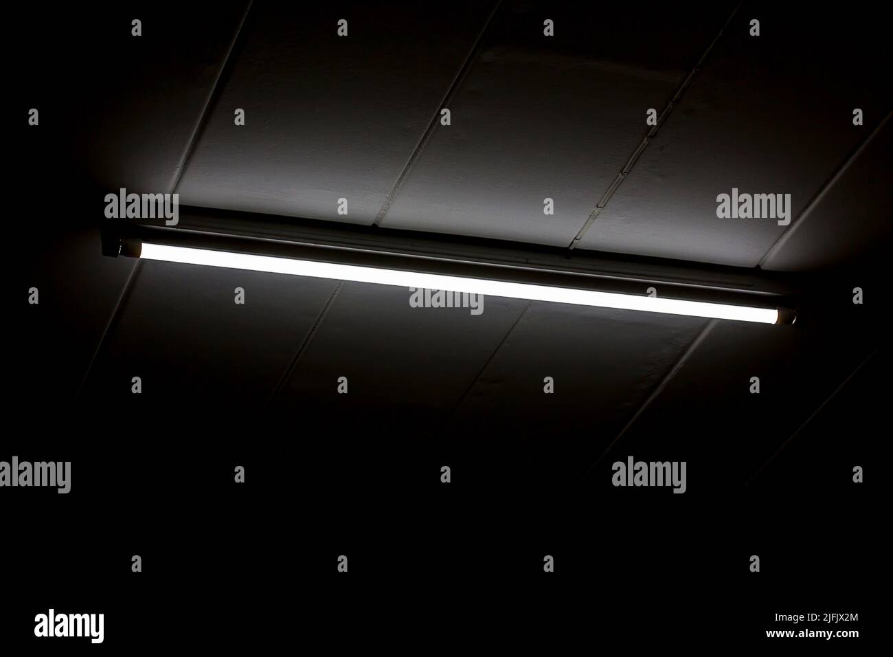 Detail of a fluorescent light tube mounted on a wall with copy space ...