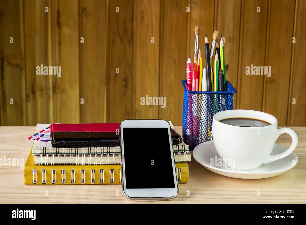 Smart phone,coffee cup,and stack of book with calendar on wooden table ...