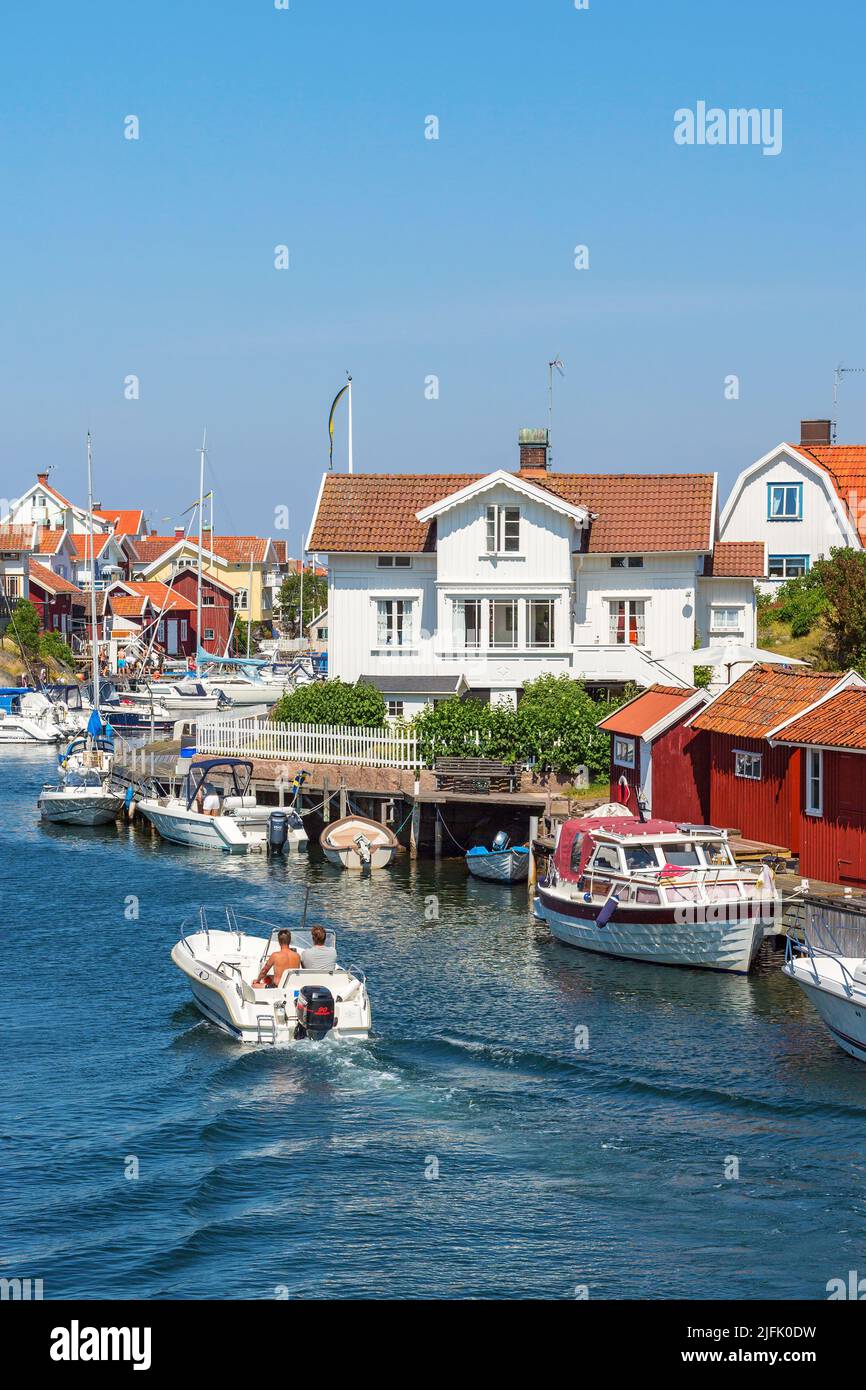 Motorboat heading in the narrow sea channel between houses Stock Photo ...