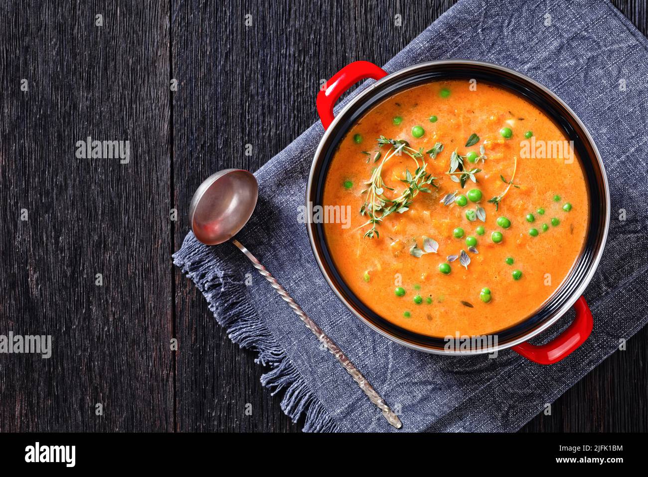 roasted yams thick soup loaded with vegetables in red pot on dark wood ...