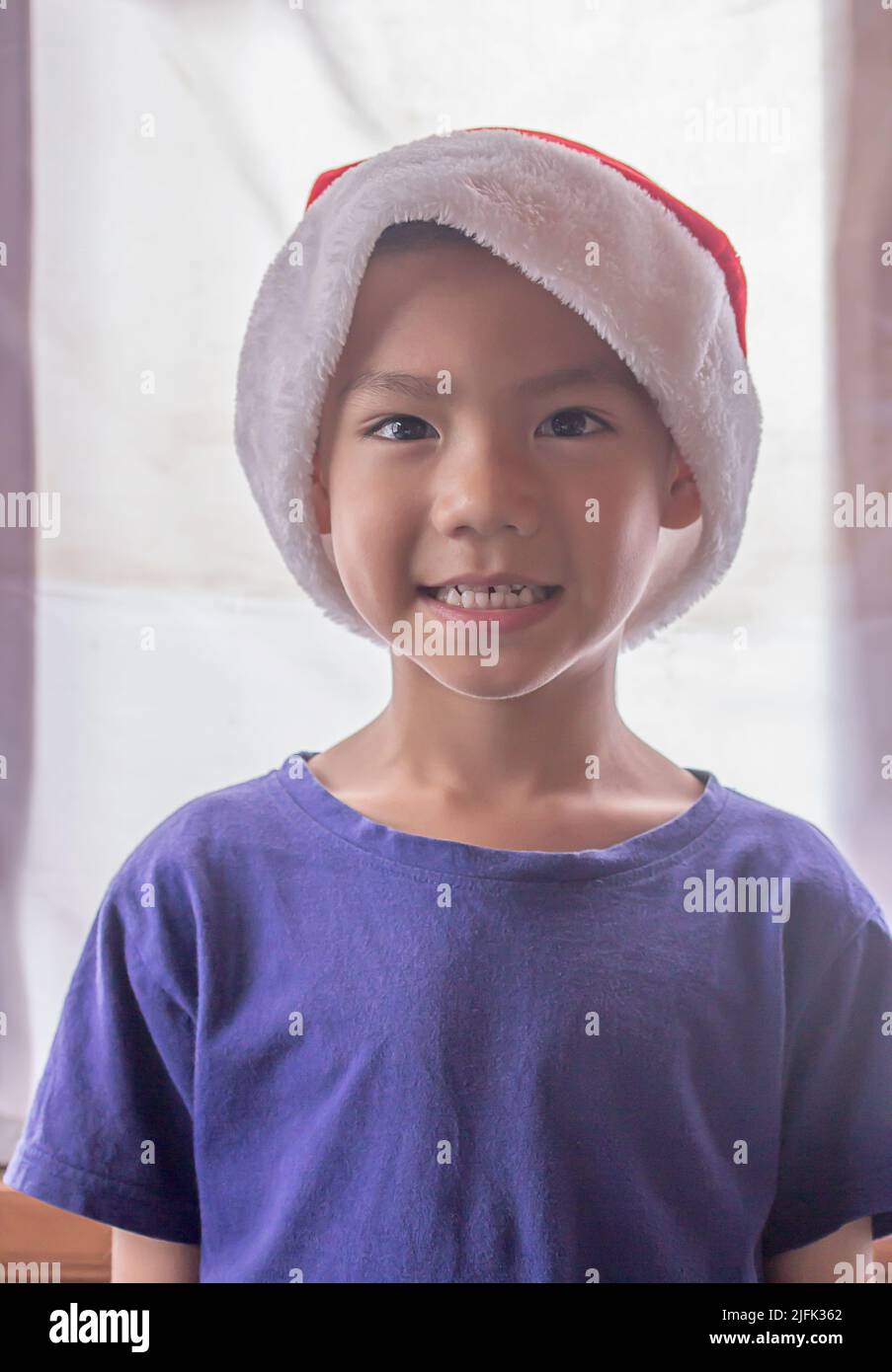 Cute asian little boy wearing a santa or christmas hat. He is smiling ...