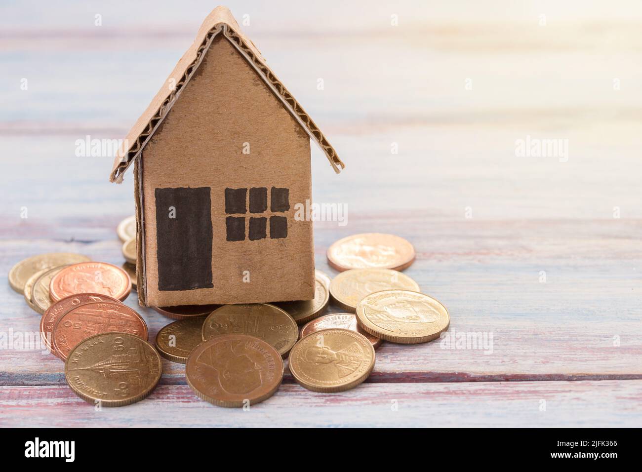 Paper house toy or cardboard house and coins on wooden table with ...