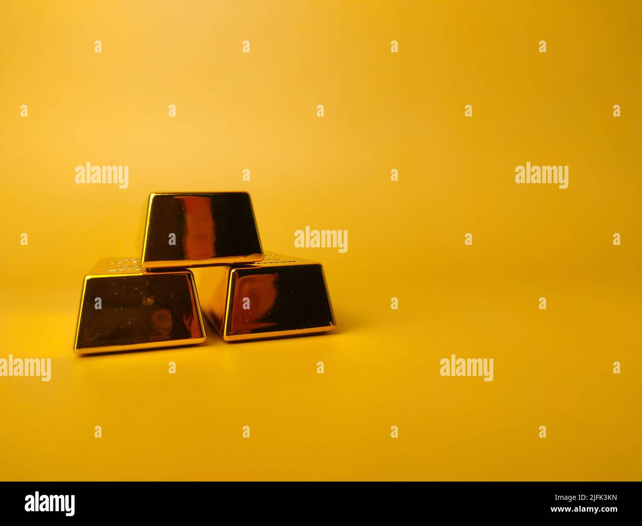 A close-up shot of gold bars on a yellow background with copy space ...