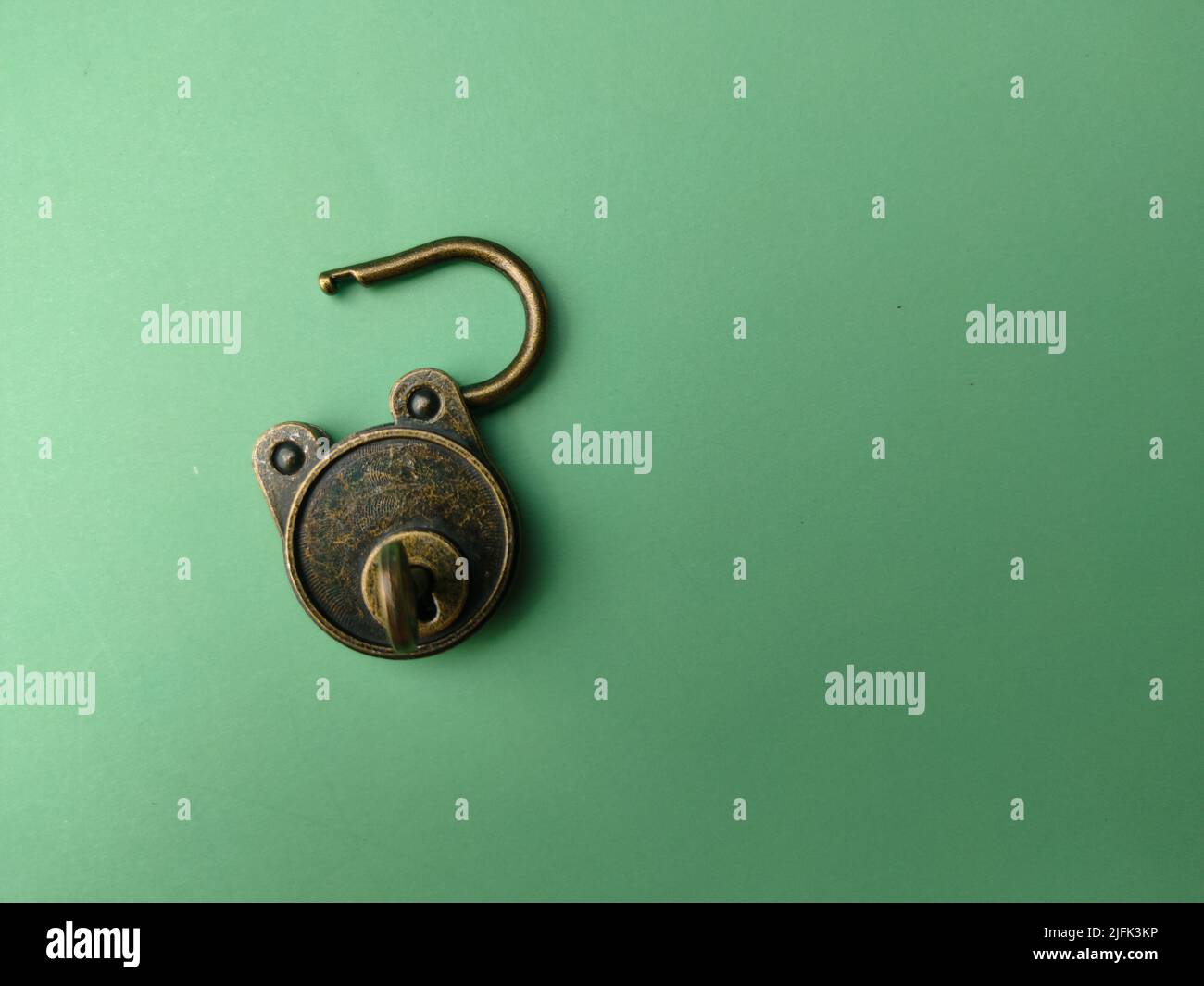 A bronze vintage unlocked padlock on soft green paper background with ...