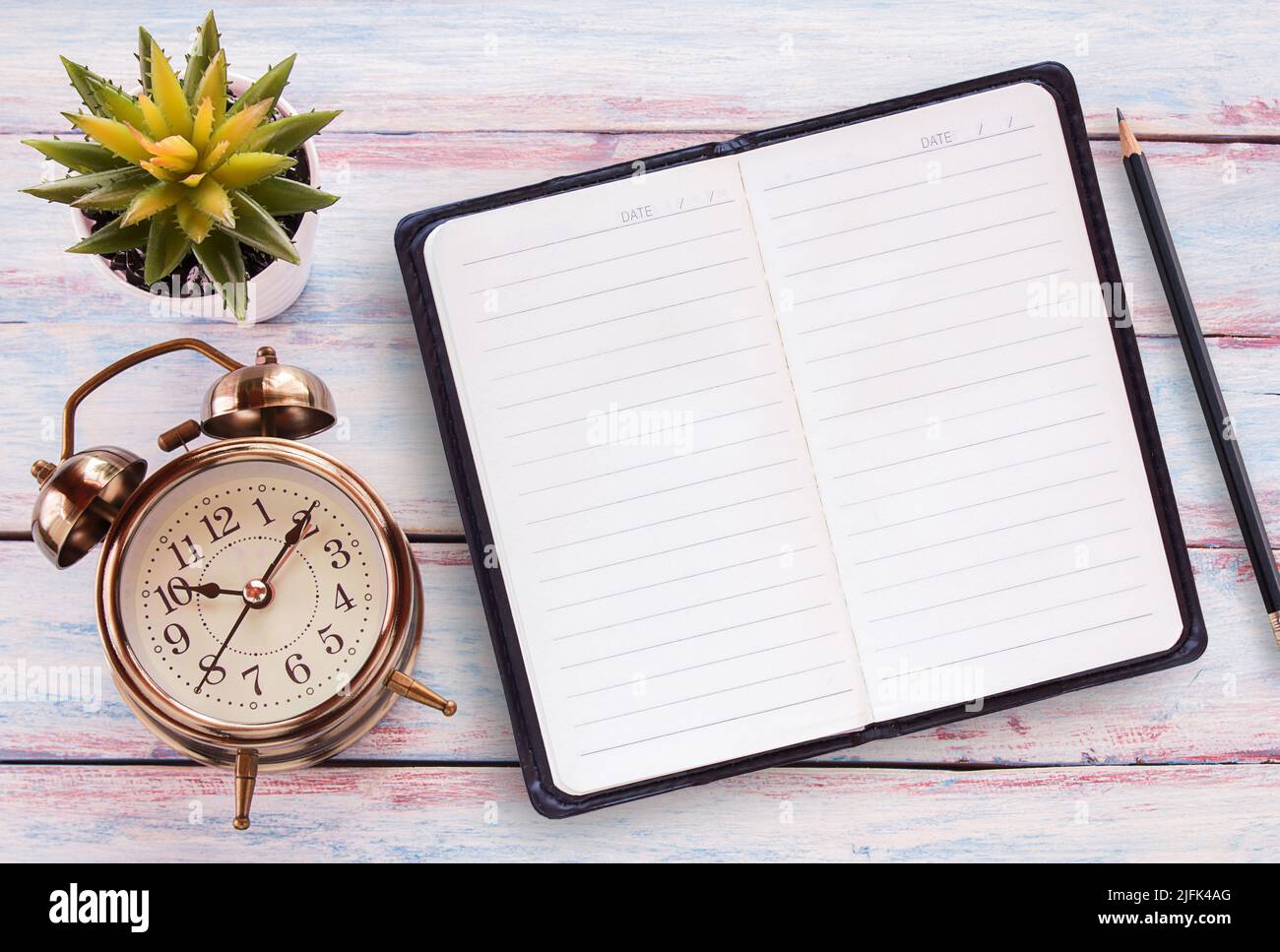 Retro alarm clock,notepad,pencil and flower on a wooden table. Photo in ...