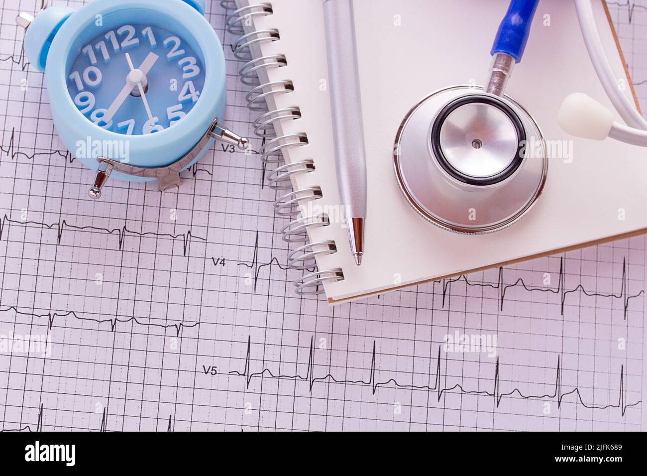 Blue stethoscope,alarm colck,notebook and cardiogram pulse trace ...