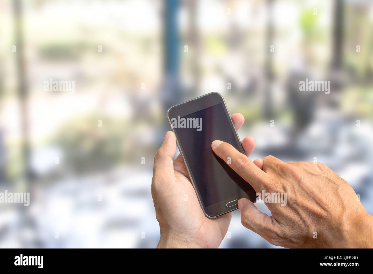 Businessman holding smartphone with blurred background. Blank space for ...