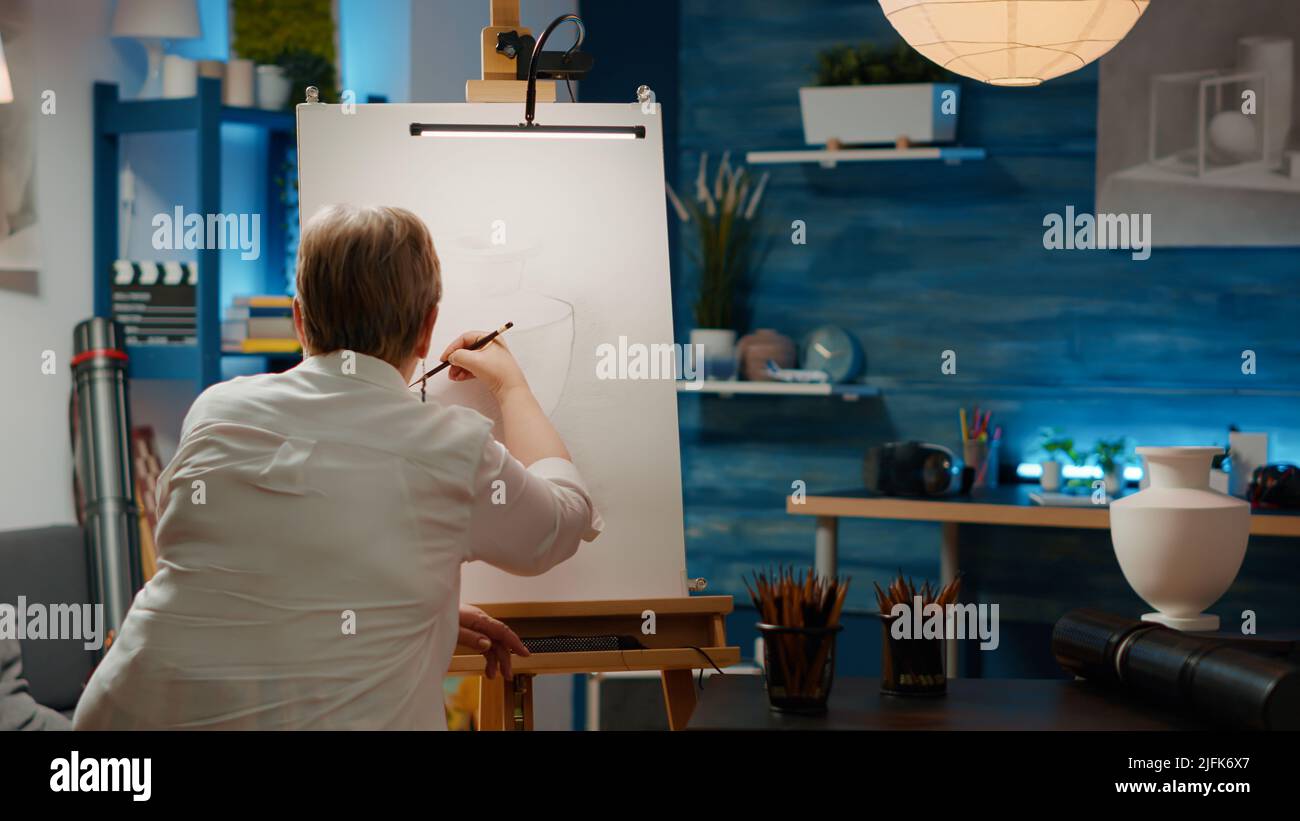 Retired woman drawing outline sketch of vase model, creating ...