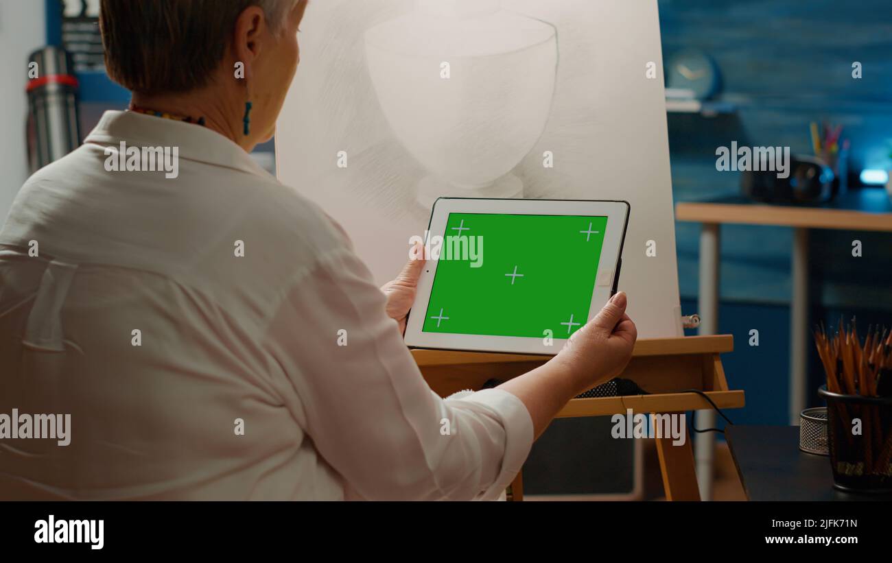 Old artist holding digital tablet with greenscreen template to draw ...