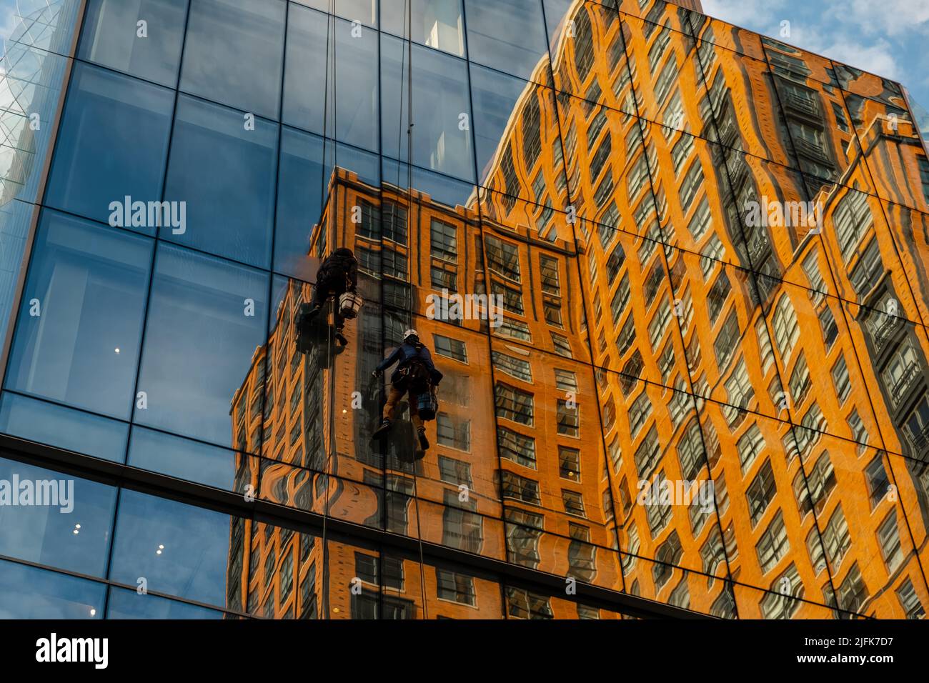 Washers wash skyscraper windows sitting on hanging seats Stock Photo ...