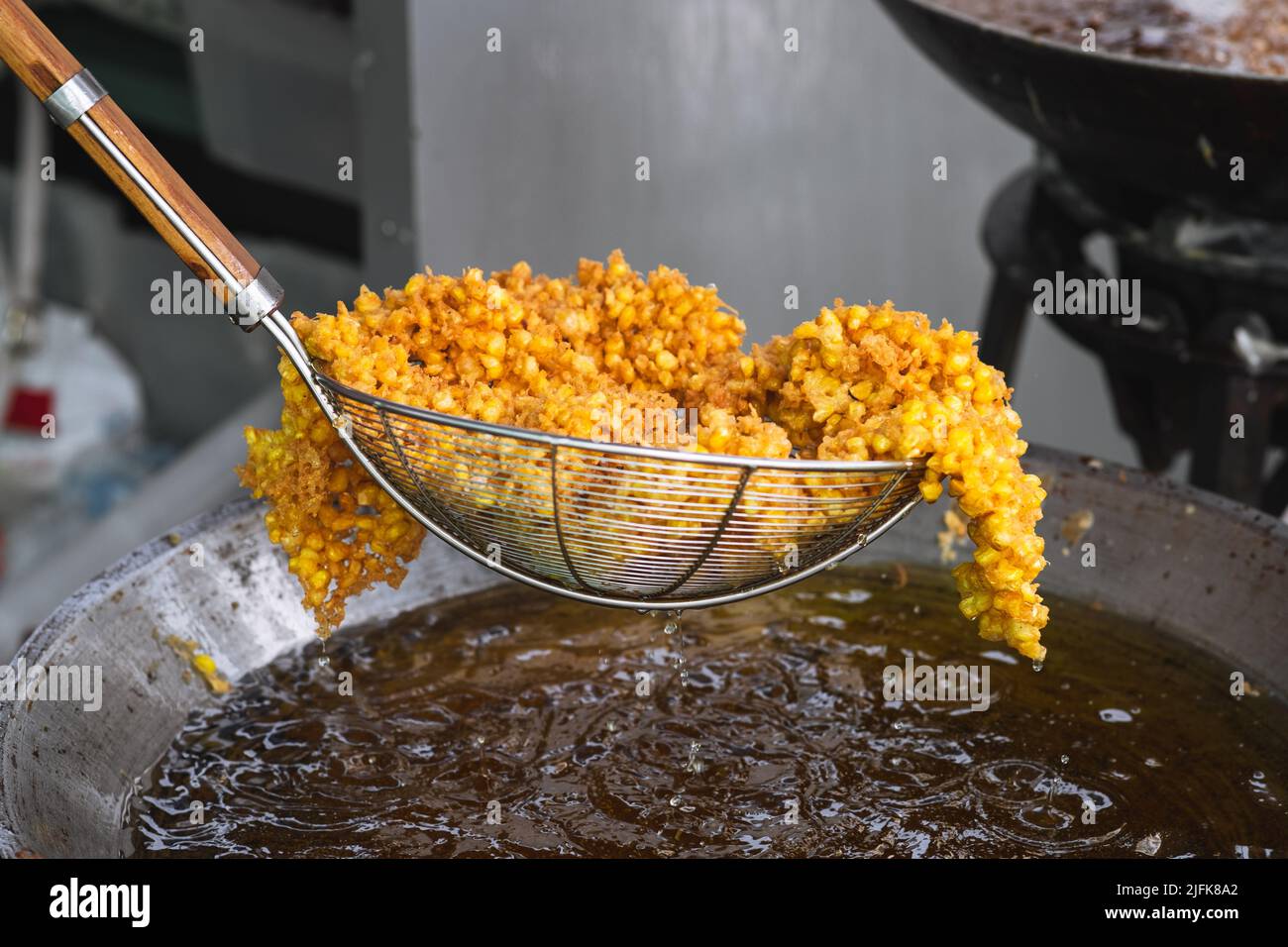 Frying corn in hot oil. Cooking crispy deep fried corn, vegetarian food ...
