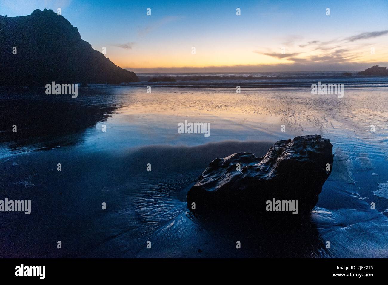 Rocks in the surf of Pfeiffer beach, around sunset. Deep yellow orange ...