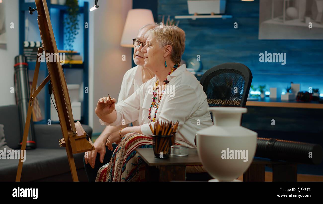 Senior man and woman looking at vase design to draw masterpiece model ...