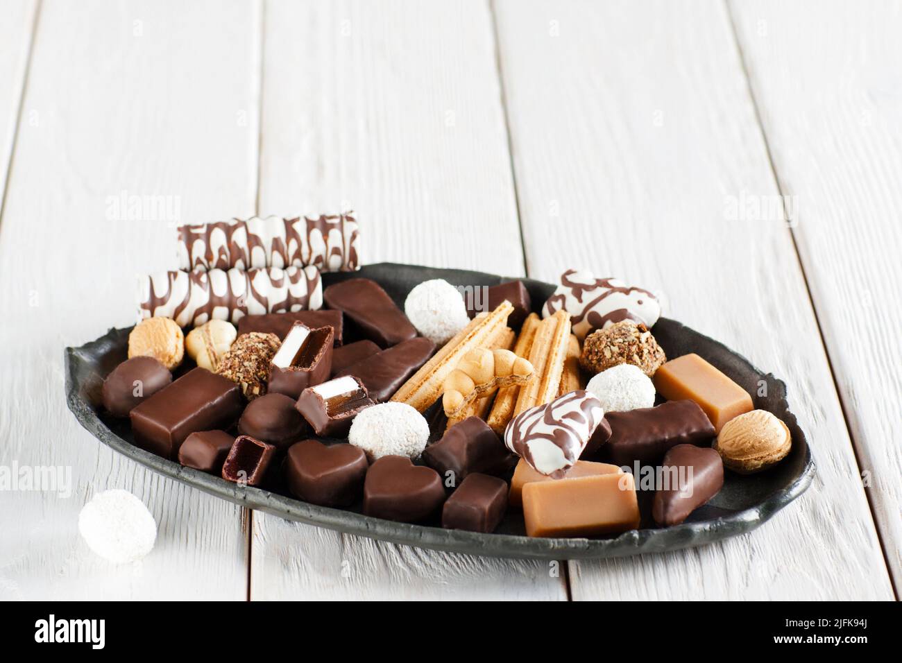 Assorted chocolate candies on black plate Stock Photo - Alamy