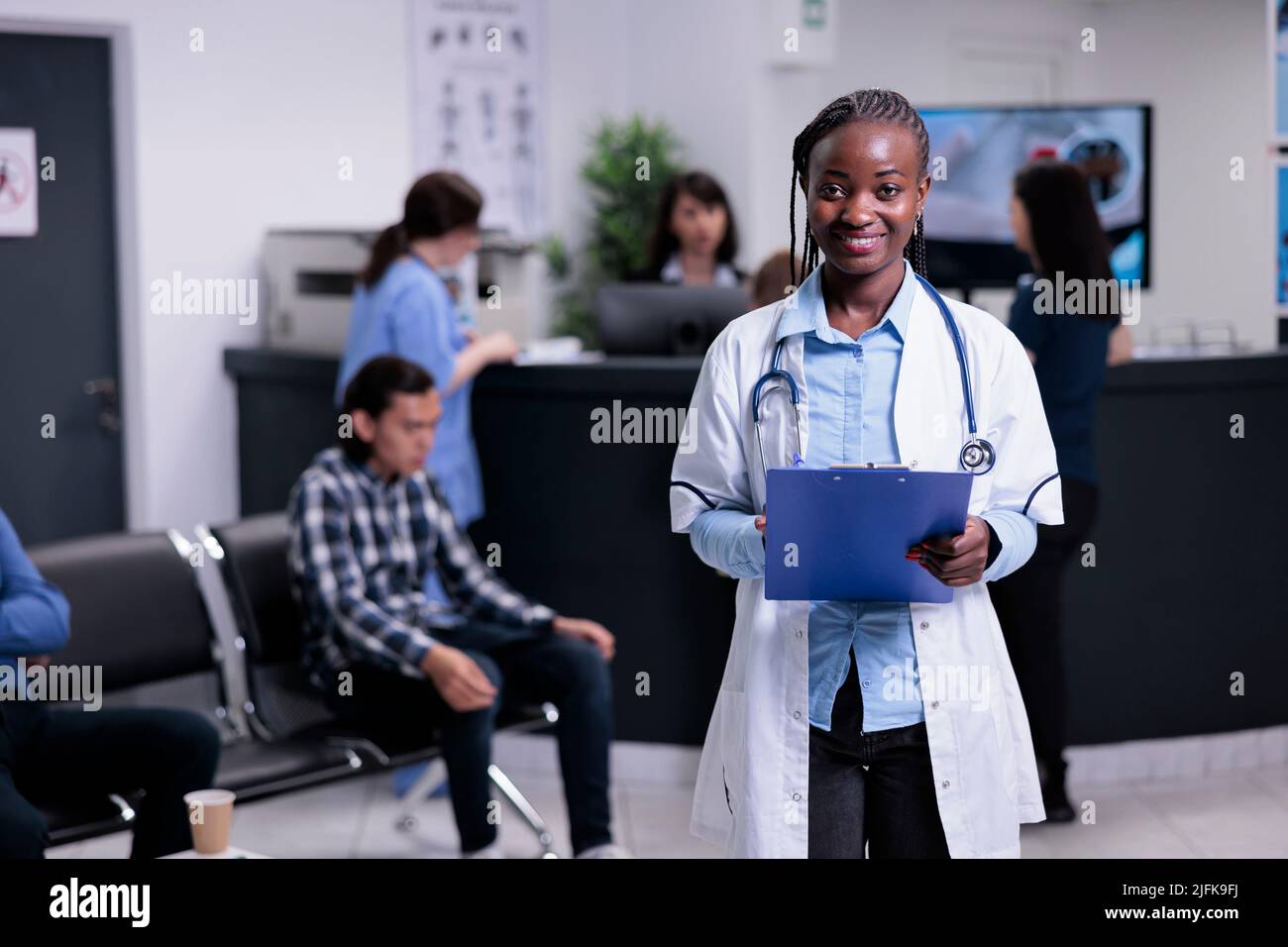 Portrait of smiling doctor with stethoscope in busy hospital reception ...