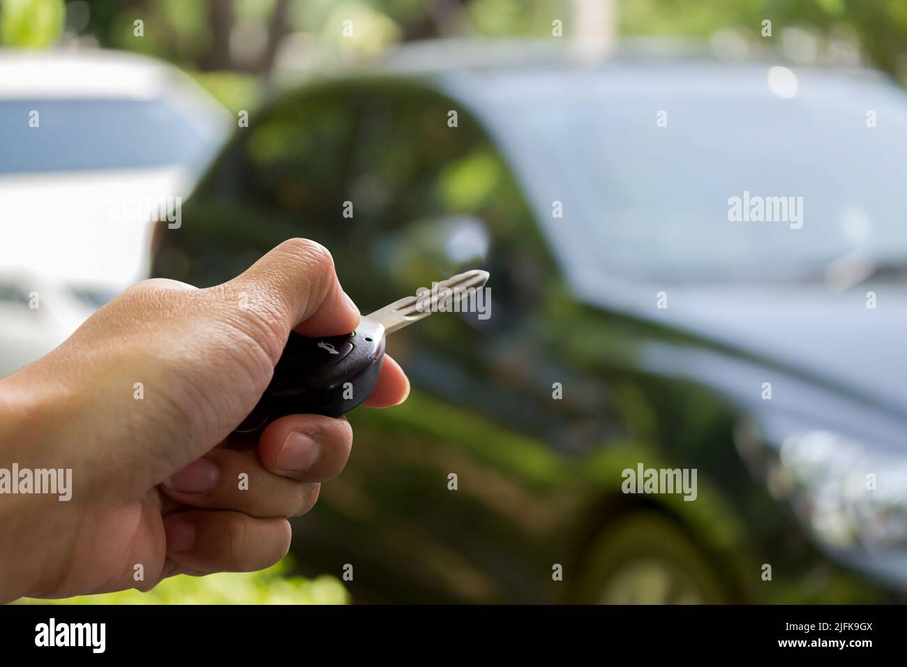 Female hand holding car key ready to start a new car with blurred car ...