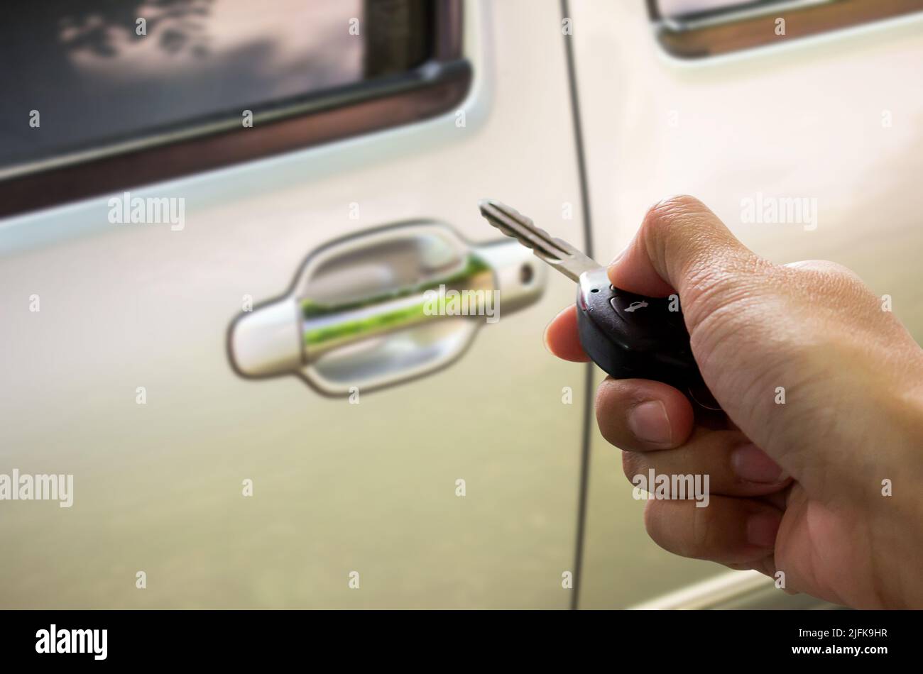 Femalel hand holding car key ready to start a new car with blurred car ...