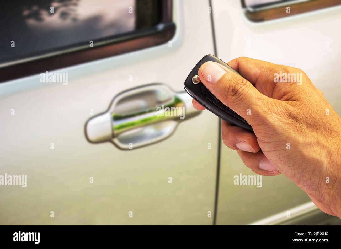 Man hand holding car key ready to start a new car with blurred car ...