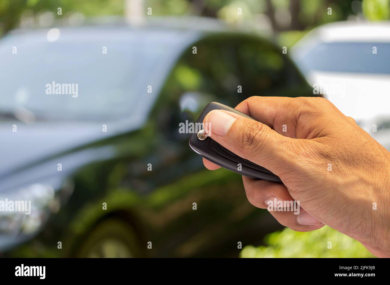 Man hand holding car key ready to start a new car with blurred car ...