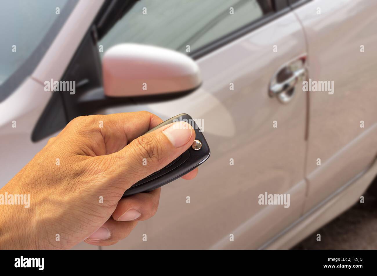 Man hand holding car key ready to start a new car with blurred car ...