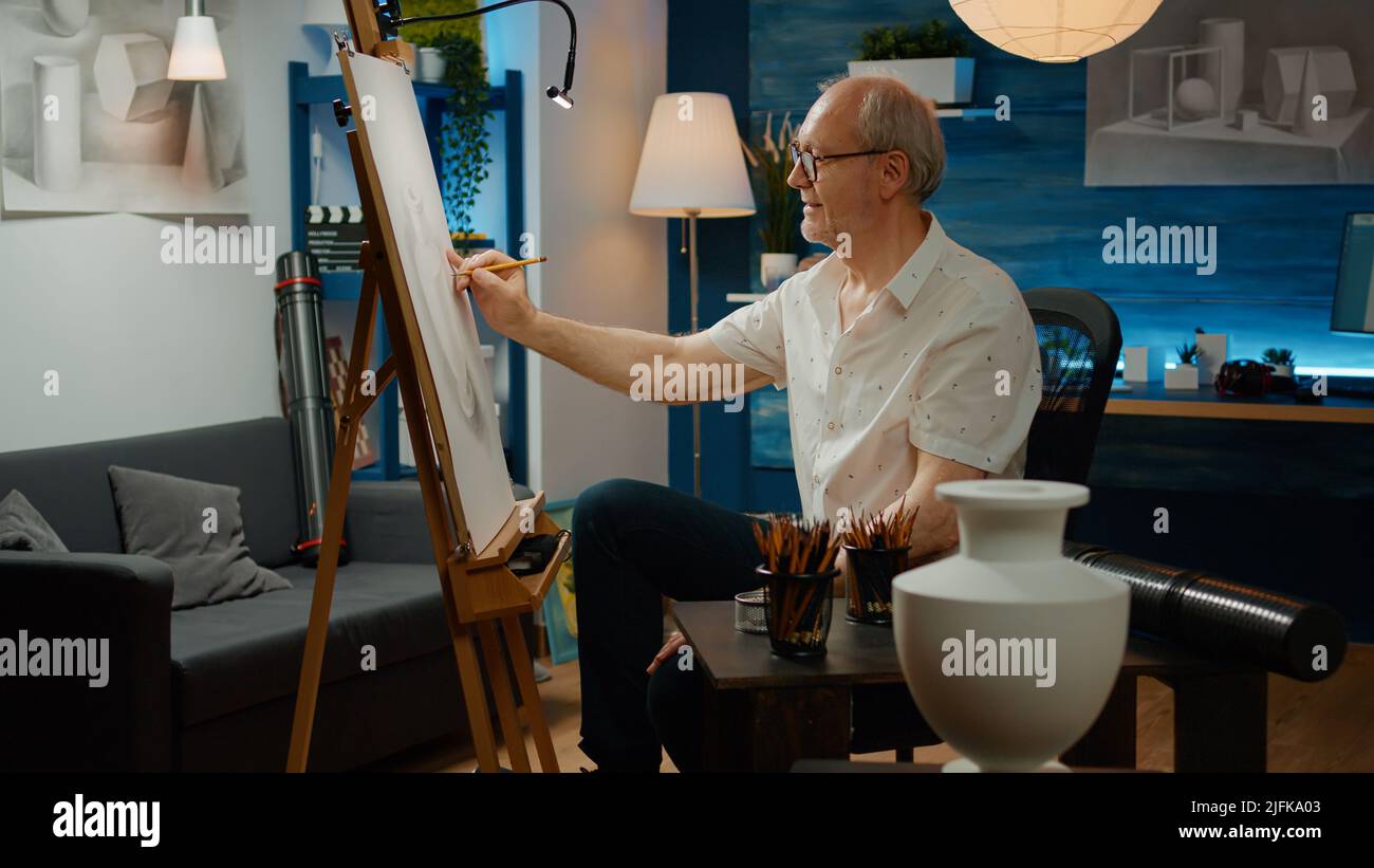 Senior adult using pencils to draw vase on white canvas, creating ...
