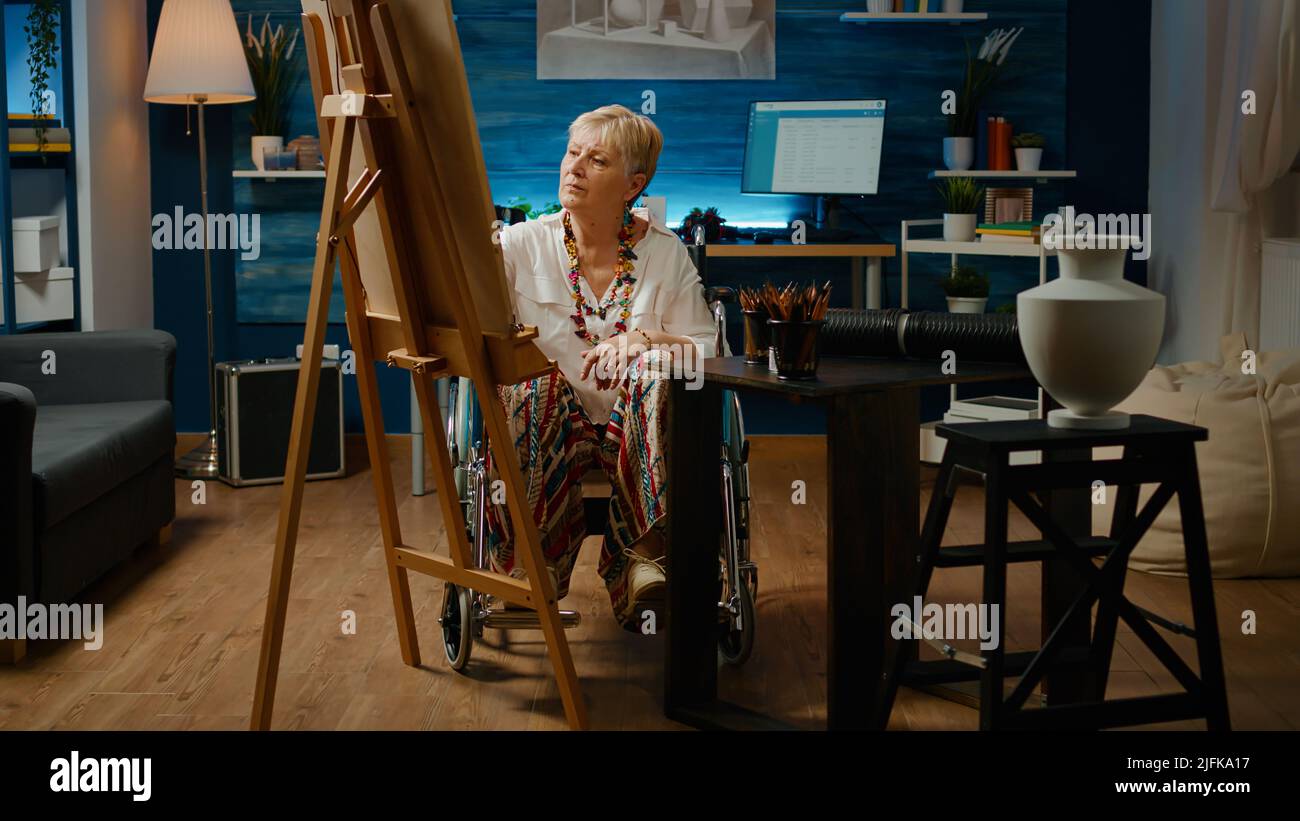 Old person with physical impairment drawing artwork design on canvas ...