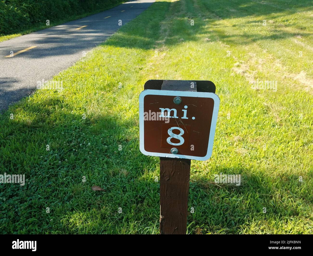 a brown 8 mile sign or mile marker in the grass near trail Stock Photo ...