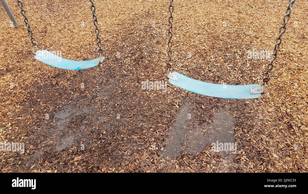 blue seat on swing with water puddle and wet mulch Stock Photo - Alamy