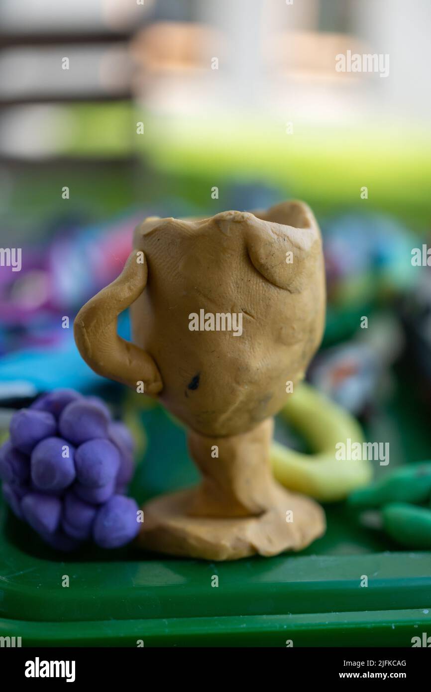 A vertical view of handmade small a golden cup made of clay Stock Photo ...