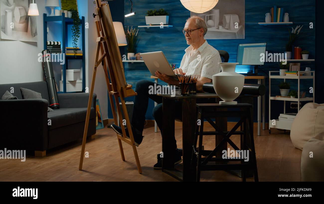 Old person browsing internet to find artistic inspiration on laptop ...