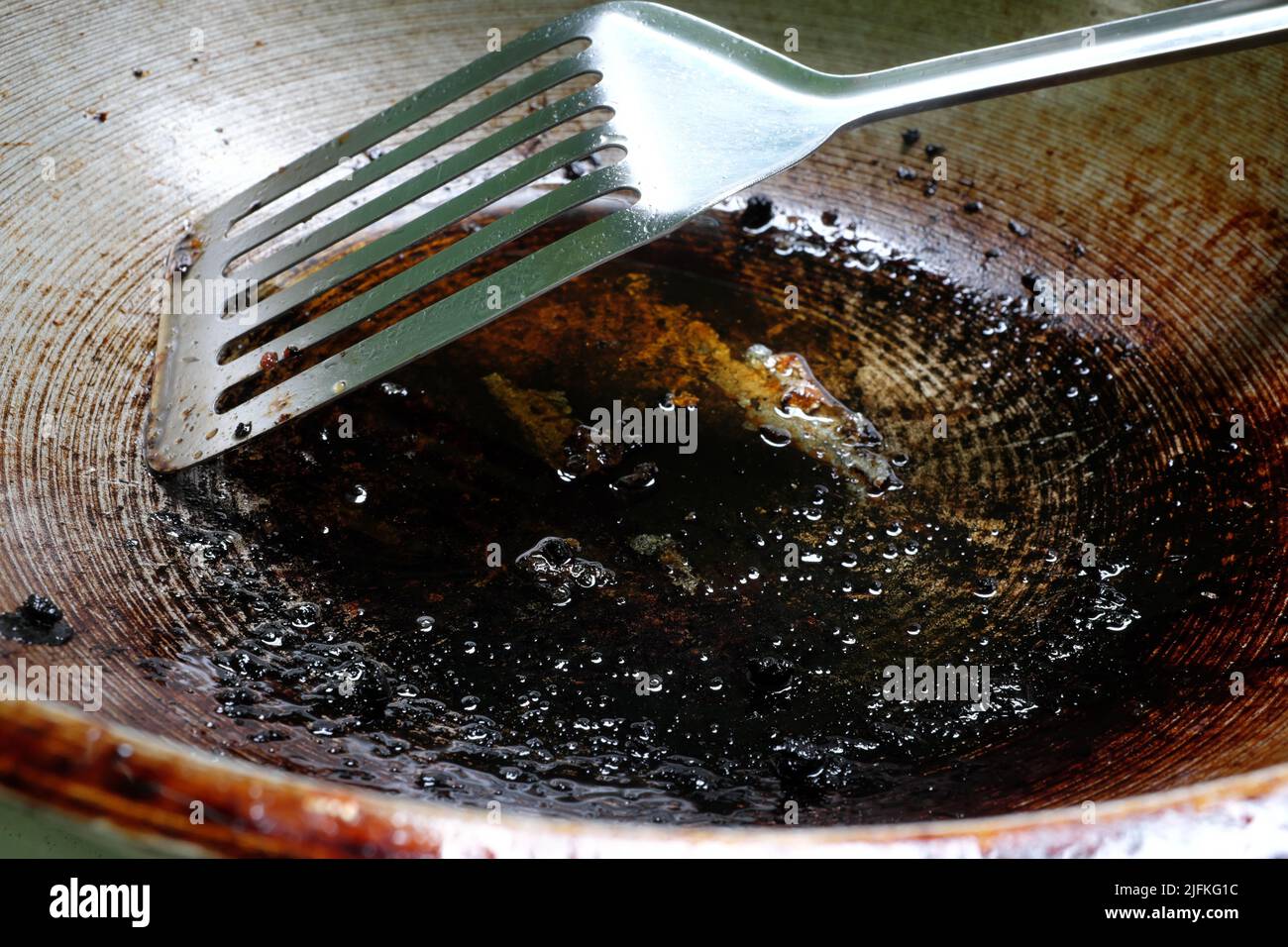 Closeup of burnt, scorched and greasy pan or wok with cooking oil in ...