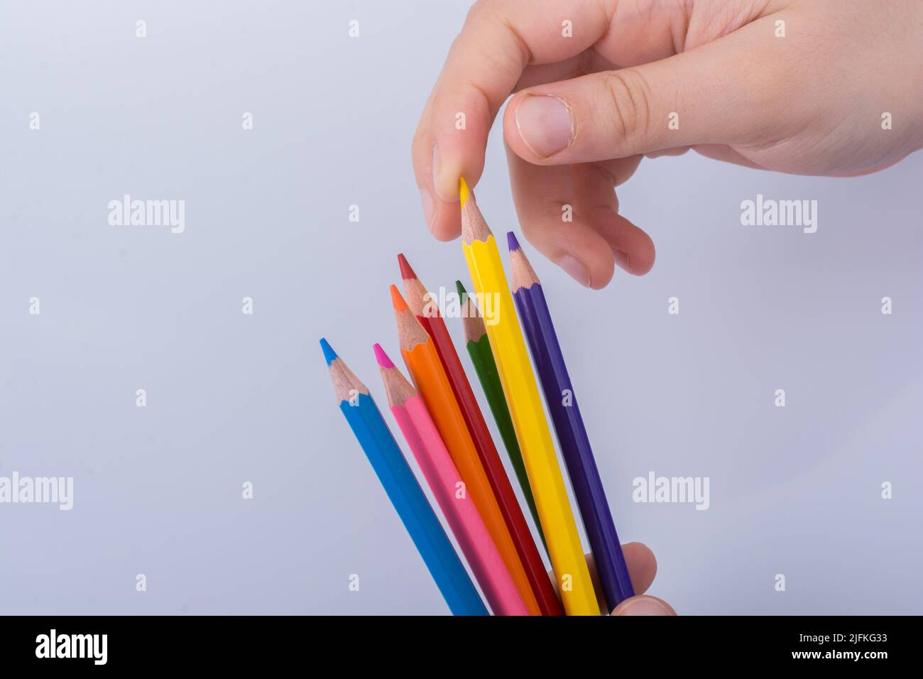 Hand holding color Pencils placed on a white background Stock Photo - Alamy