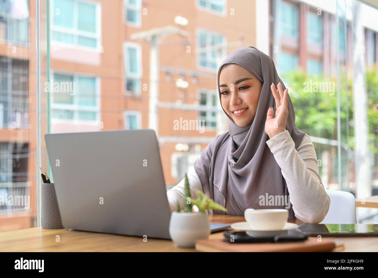 Muslim woman in hijab having video call on her laptop computer, sitting ...
